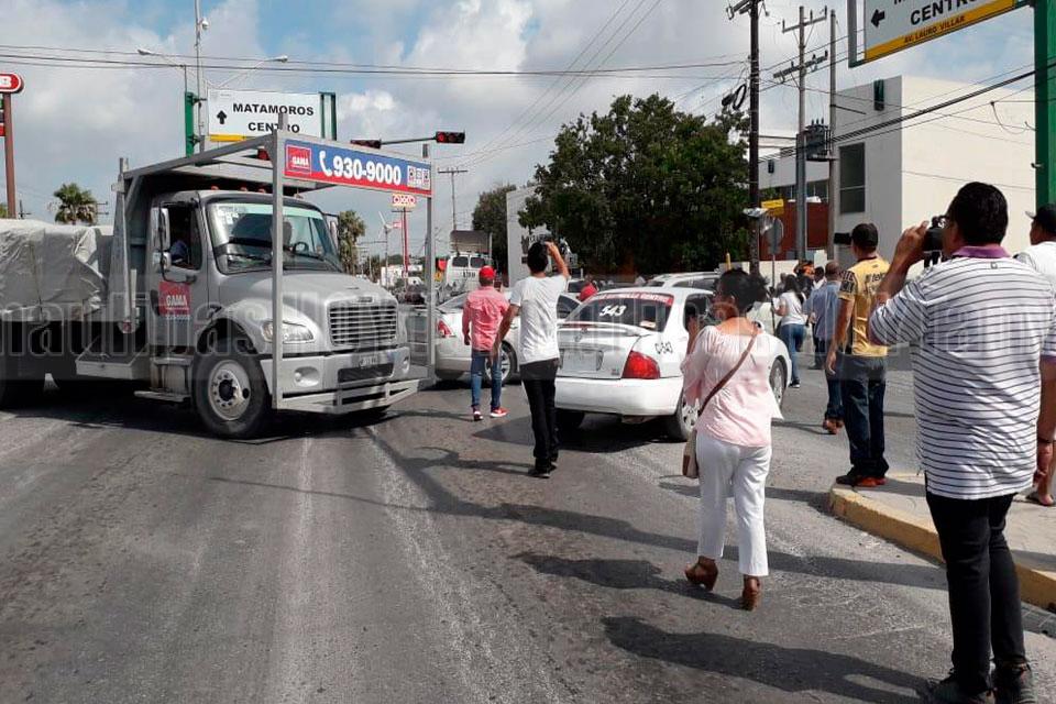 Hoy Tamaulipas - Taxistas bloquean por minutos una avenida en Matamoros